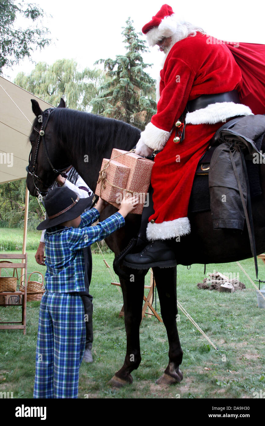 Santa delivering Christmas presents on horseback to a little boy in a ...