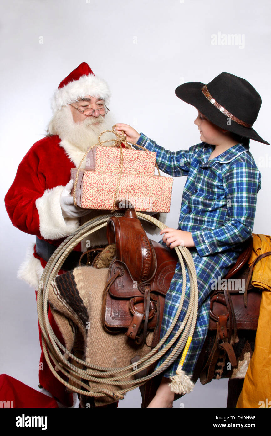 Western Santa delivering Christmas presents to a little boy on a saddle ...