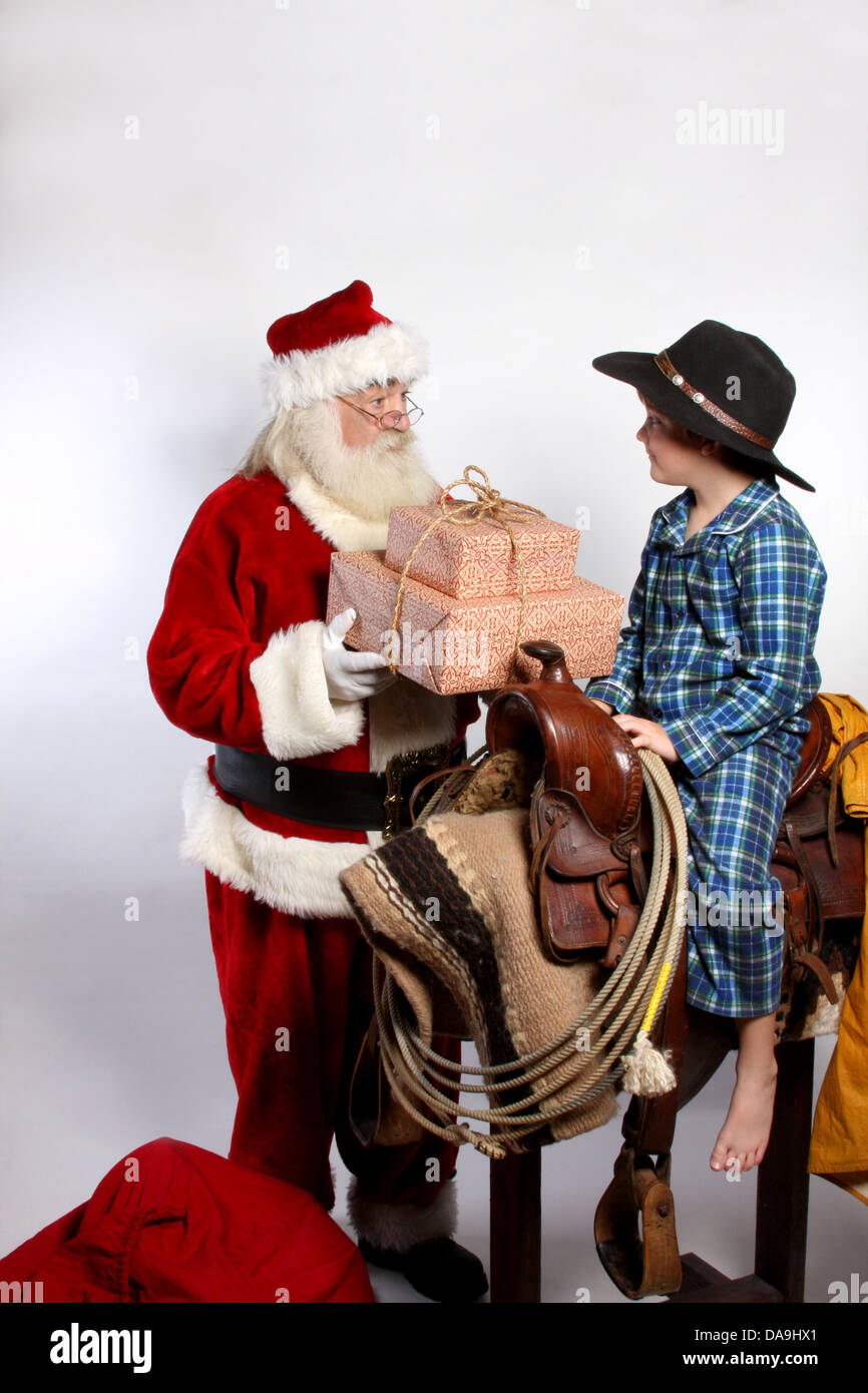 Western Santa delivering Christmas presents to a little boy on a saddle ...