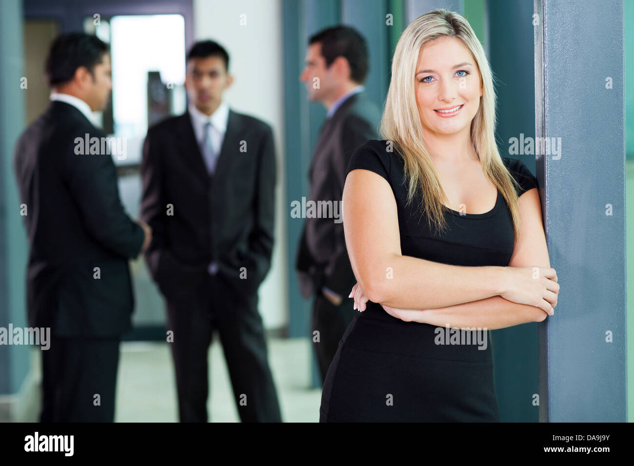 attractive blond corporate worker standing in office Stock Photo - Alamy