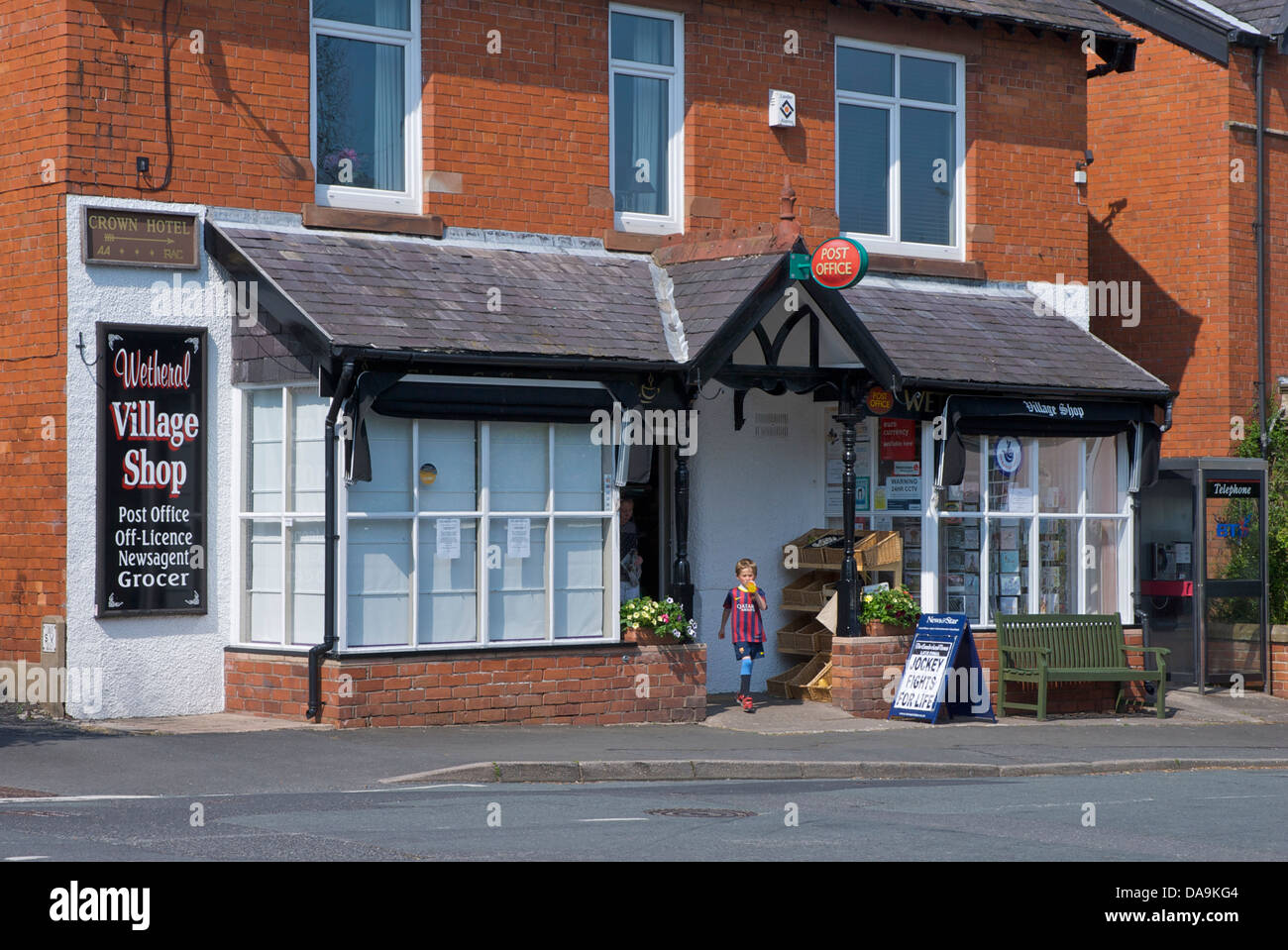 Young boy walking out of the village shop and post office in Wetheral ...