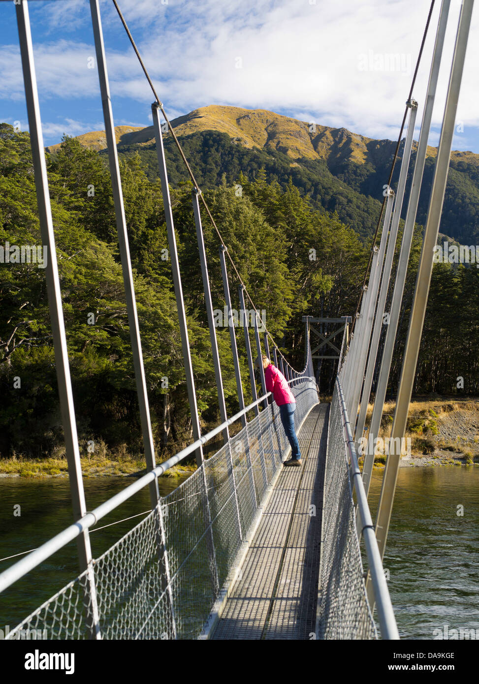 A woman on the suspension bridge crossing the Mararoa River; Scene from ...
