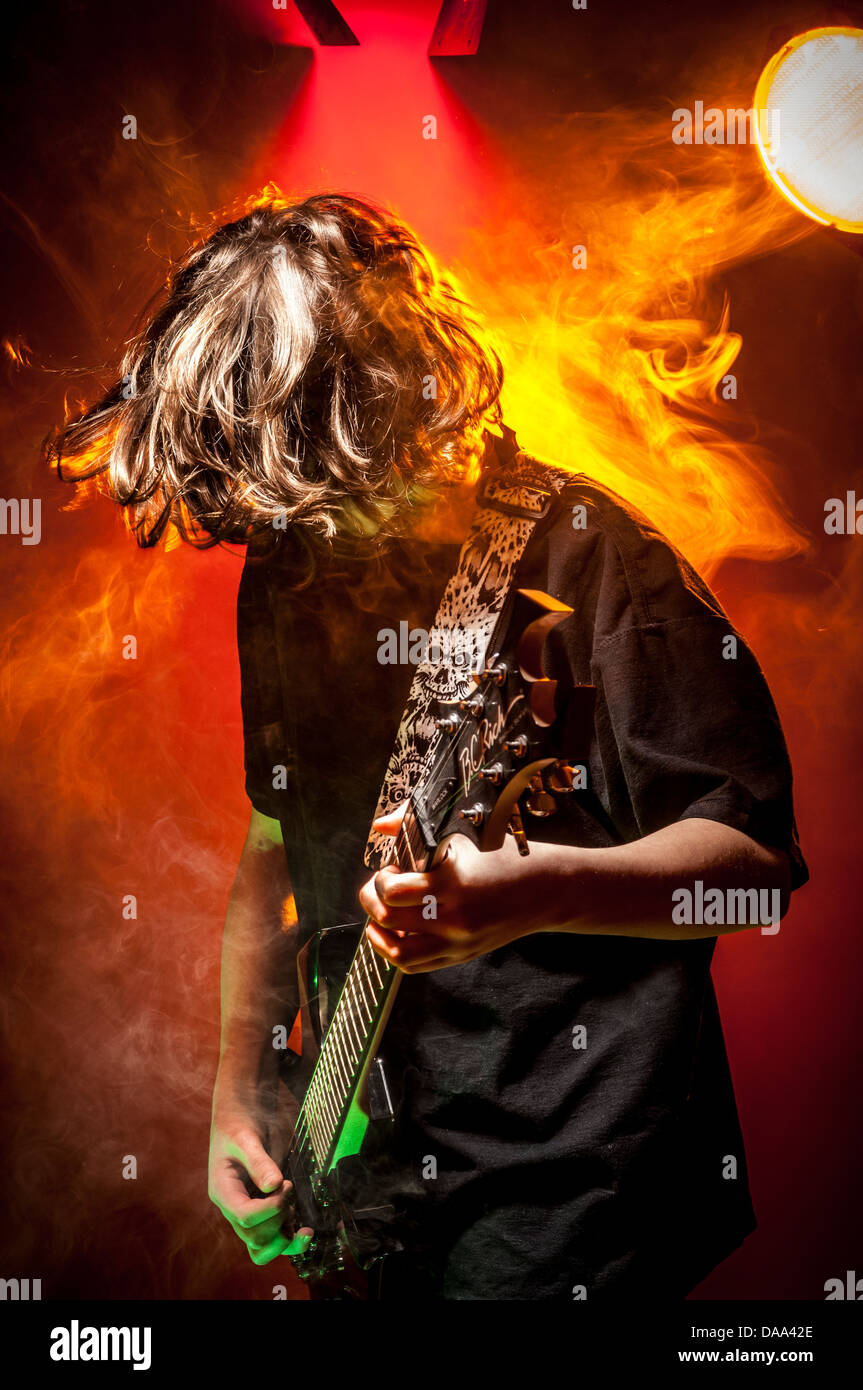 Unidentifiable young caucasian male musician playing guitar on stage ...