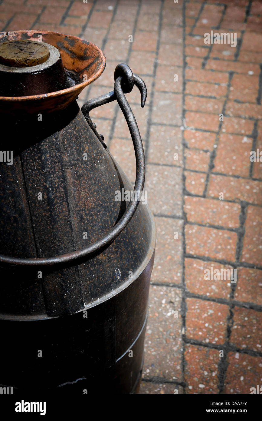 Retro milk copper iron can with handle, black painted on paved surface ...