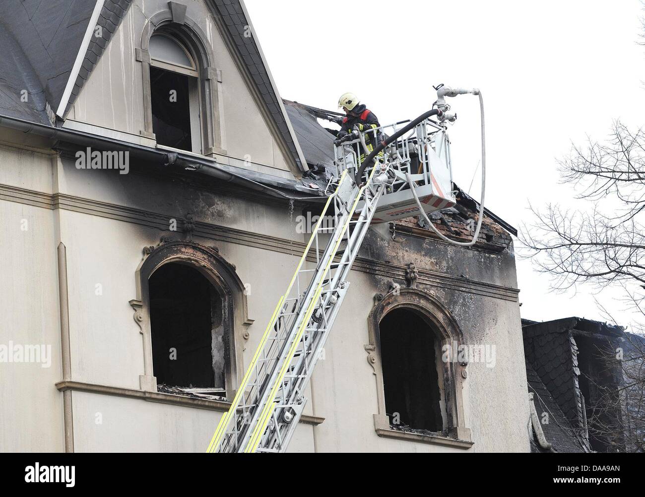 A fire fighter stands in a rescue basket in front of a tenement in ...