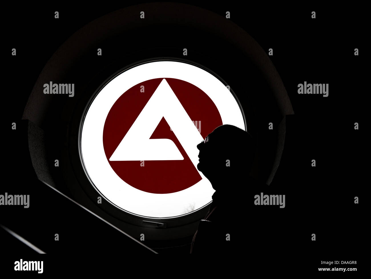 A man stands in front of the logo of the German 'Employment agency' in ...