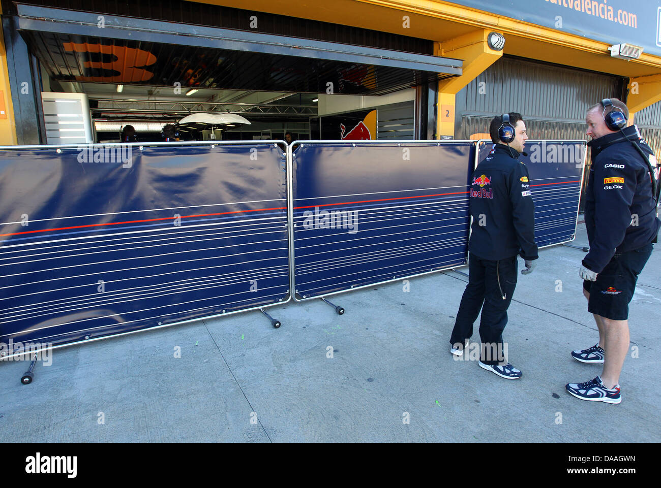 Mechanics stand in front of the Red Bull pit, that is covered from the ...