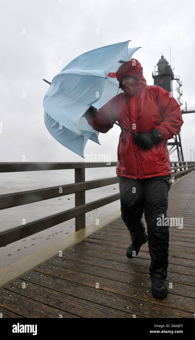 A young woman struggles with the wind and her umbrella on the quay in ...