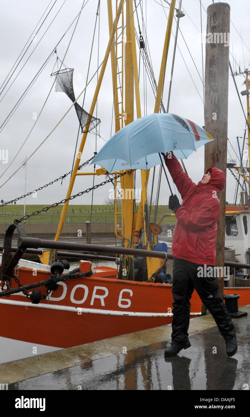 A young woman struggles with the wind and her umbrella on the quay in ...