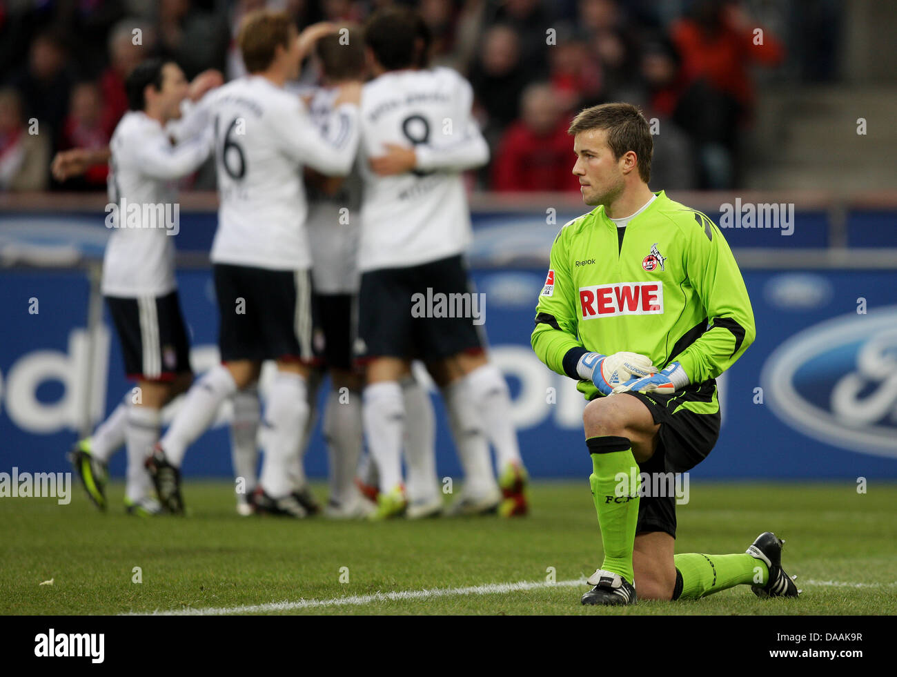 Cologne's goalkeeper Michael Rensing (R) kneels on the pitch while ...