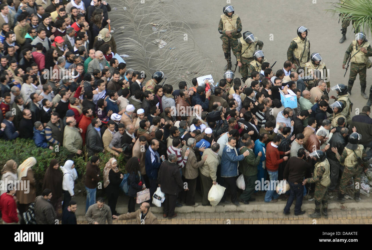 Protesters gather behind a checkpoint where Egyptian soldiers search ...
