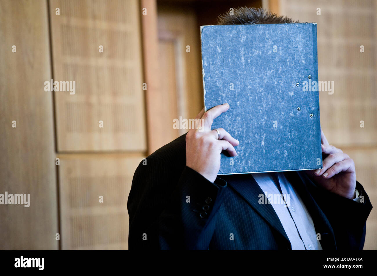 Defendant Olaf H covers his face with a folder in the courtroom at the ...