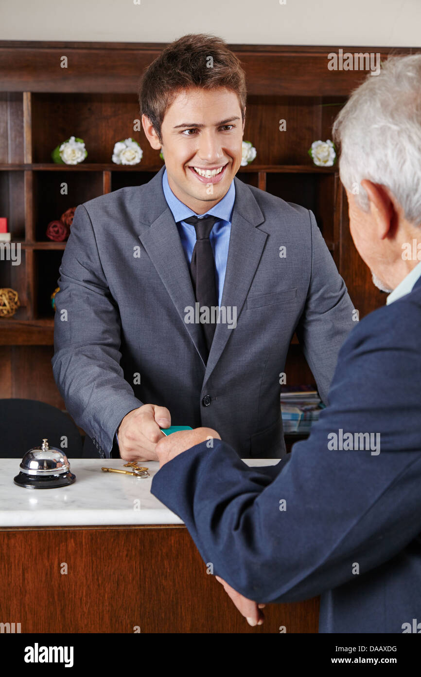 happy hotel receptionist giving key card to senior man Stock Photo - Alamy