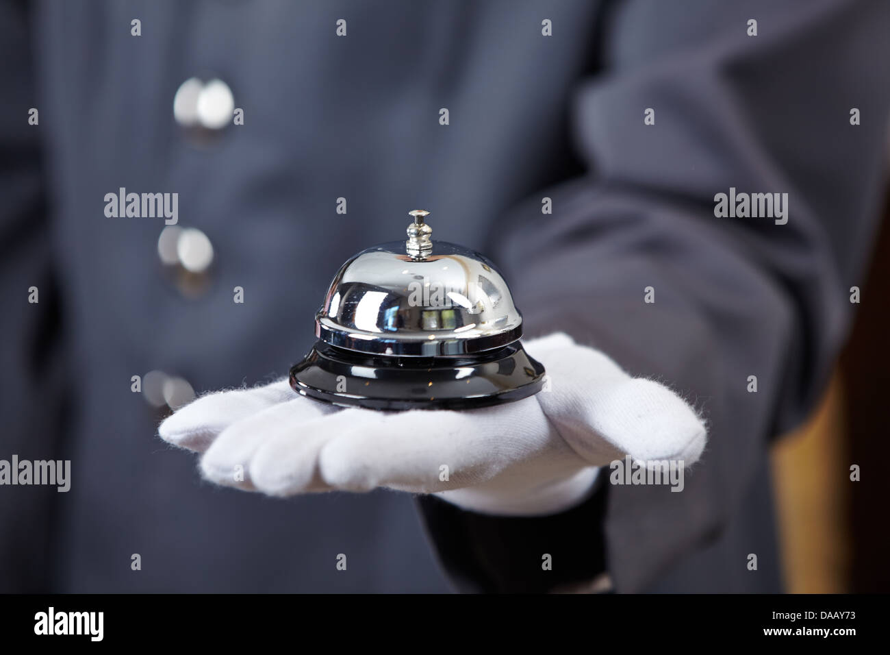 Hand of a concierge with a hotel bell Stock Photo - Alamy