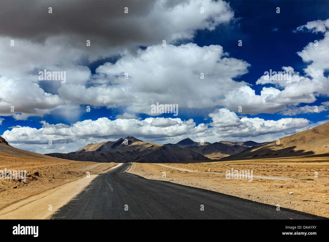 Travel forward concept background - road on plains in Himalayas with mountains and dramatic ...