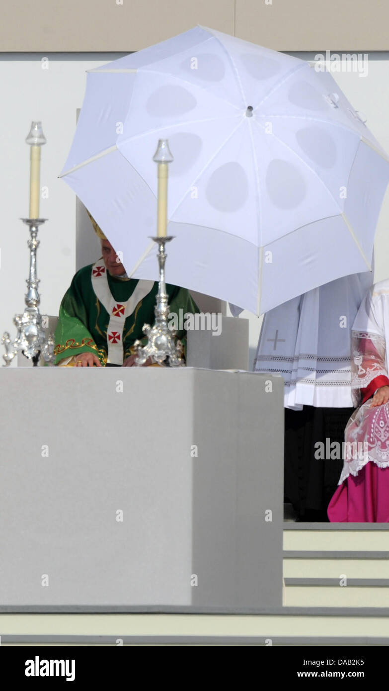 Pope Benedikt XVI. (c) is sitting under a sun umbrella at a mass at a ...