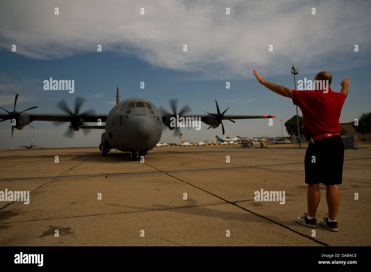 A ground crew member directs a military C-130 from the California Air ...