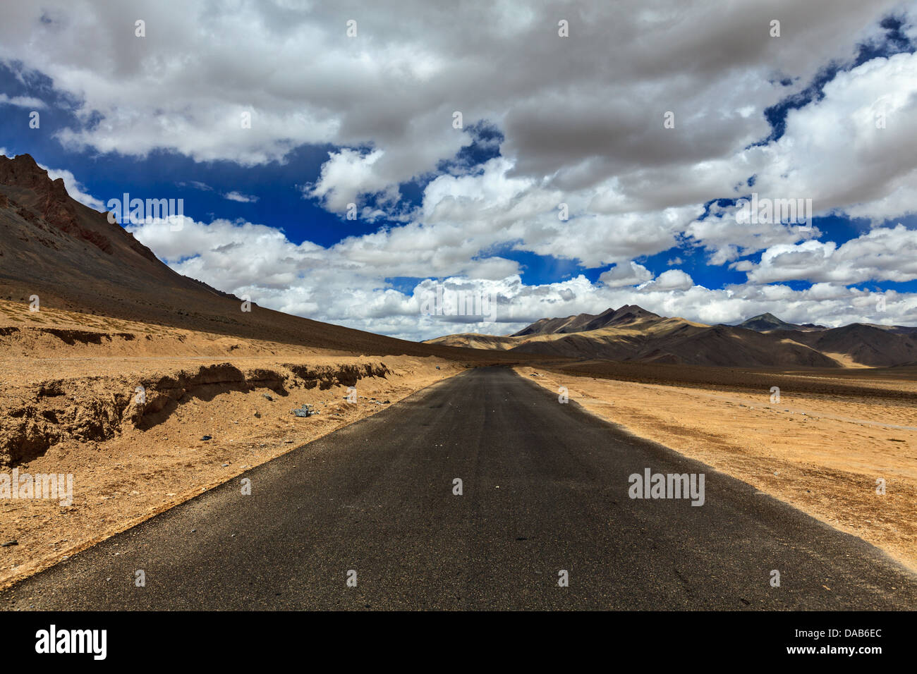 Travel forward concept background - road on plains in Himalayas with mountains and dramatic ...