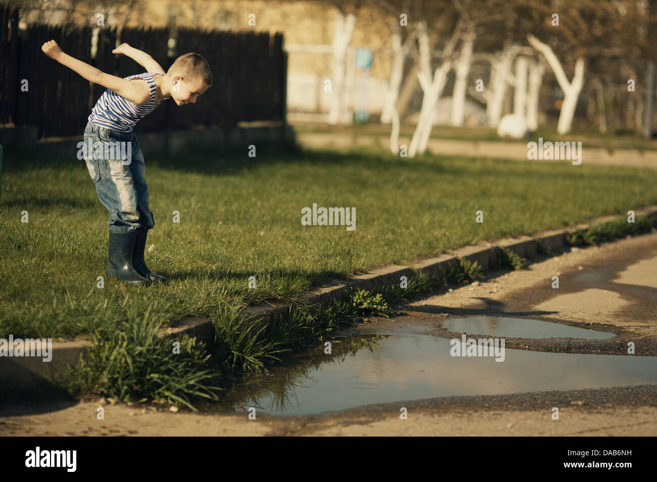 little happy boy jumping to puddle Stock Photo - Alamy