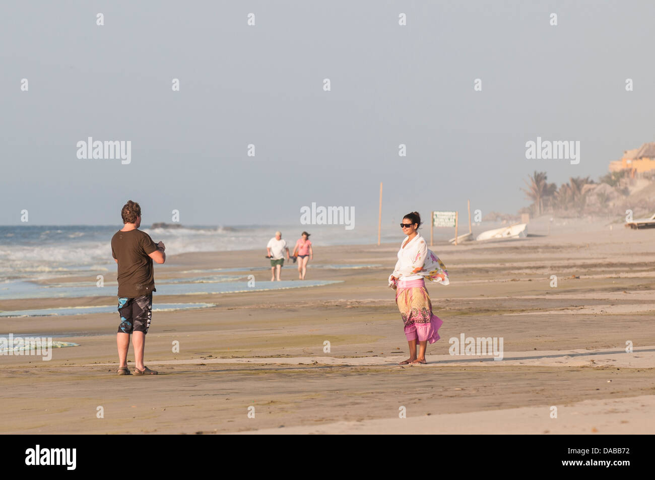 Couple taking pictures and a romantic walk on Vichayito beach at sunset ...