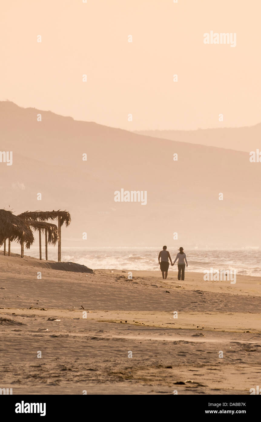 Couple holding hands take a romantic walk on Vichayito beach at sunset ...