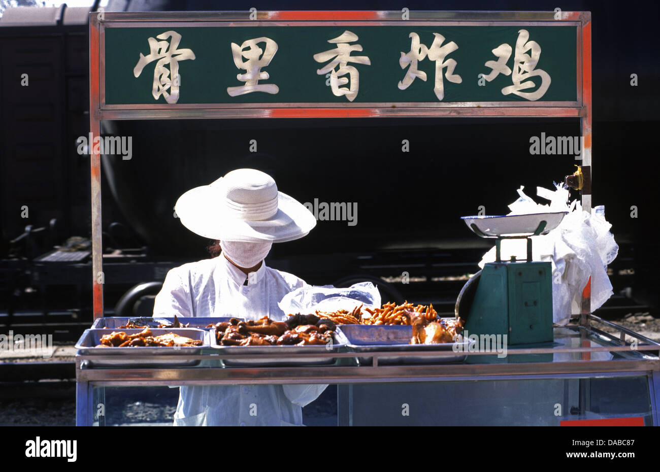 A Chinese vendor wearing a face mask for hygiene selling grilled ...