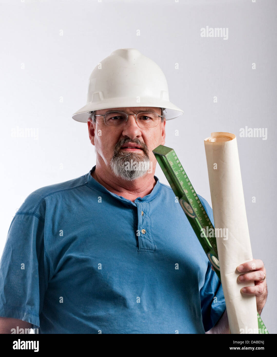 Adult construction worker wearing a hardhat and carrying some items for ...