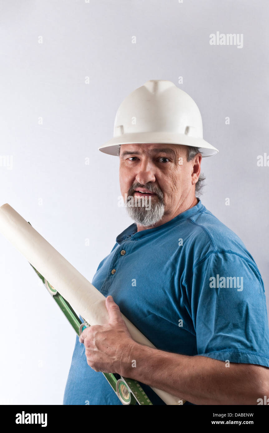 Adult construction worker wearing a hardhat and carrying some items for ...