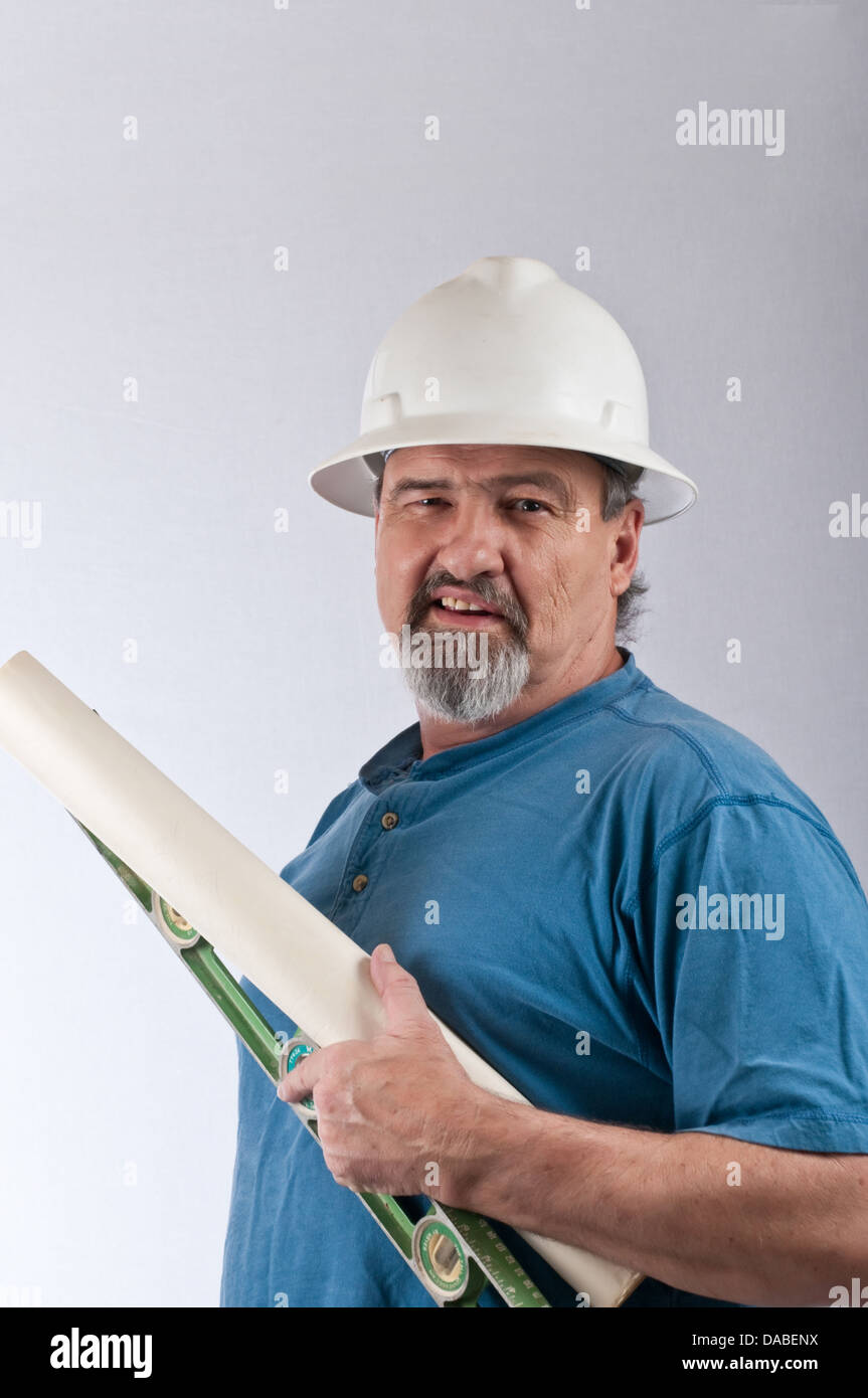 Adult construction worker wearing a hardhat and carrying some items for ...