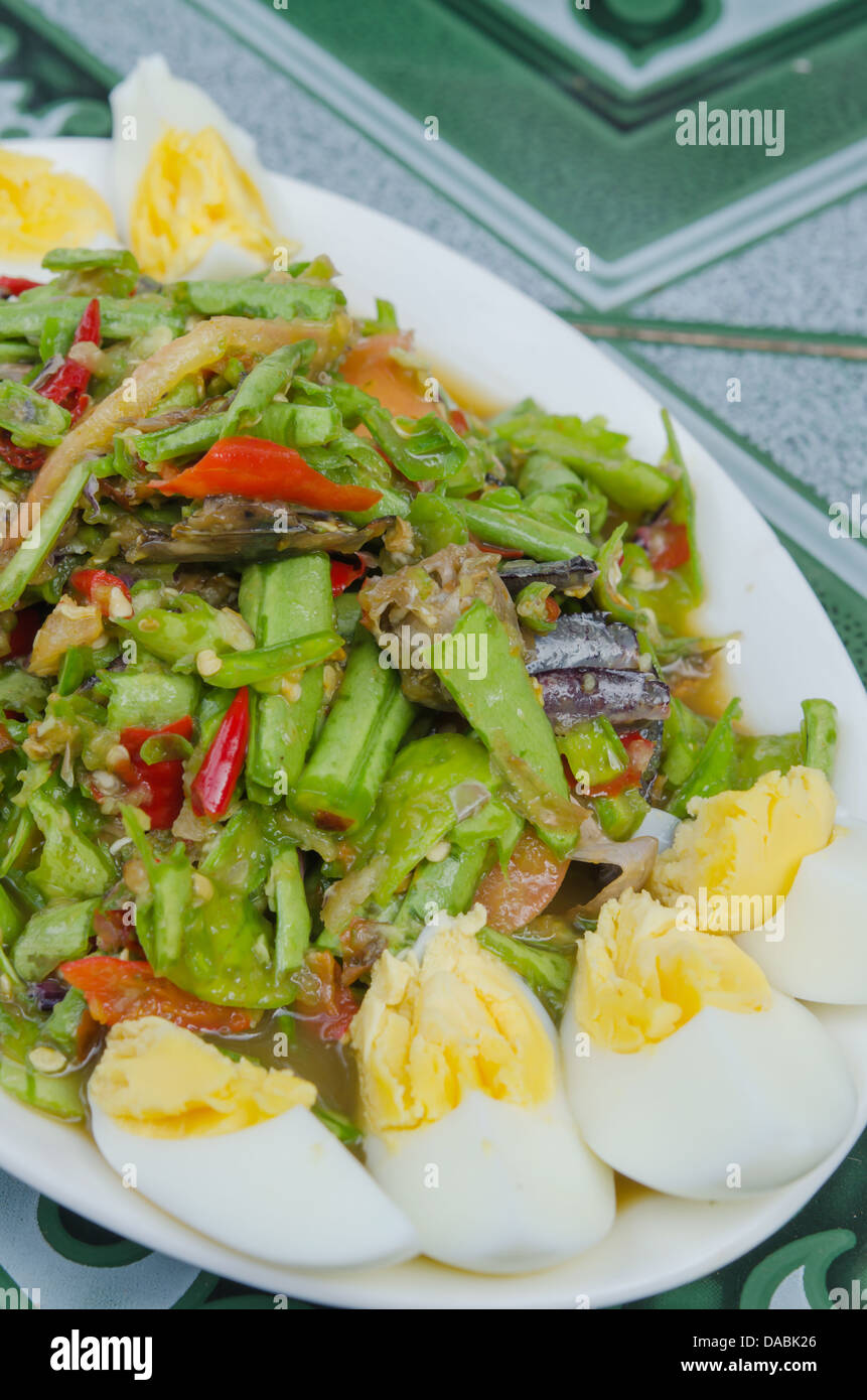String bean spicy salad served with slice boiled egg on white plate ...