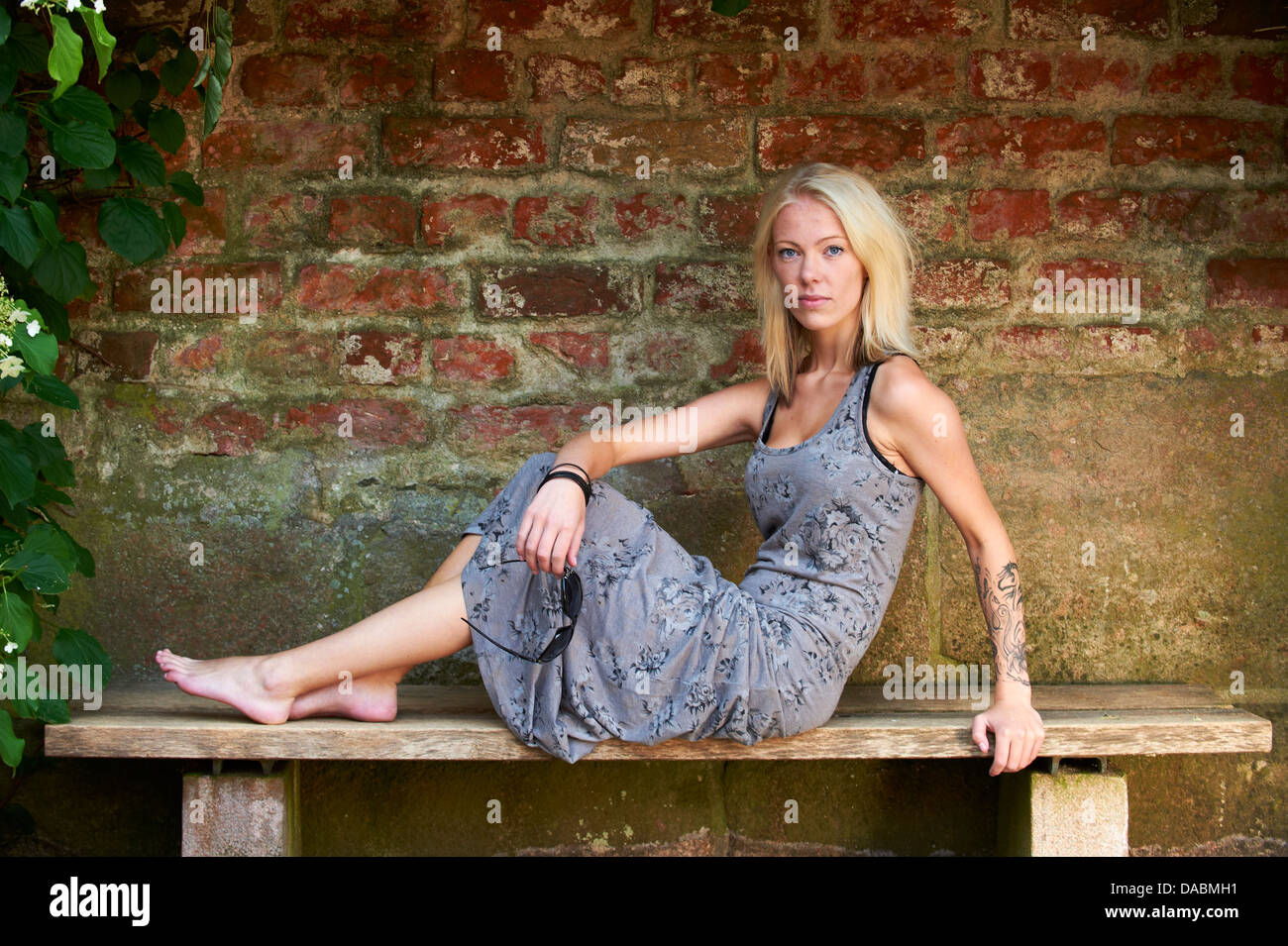 Beautiful young girl sitting on a bench Stock Photo - Alamy