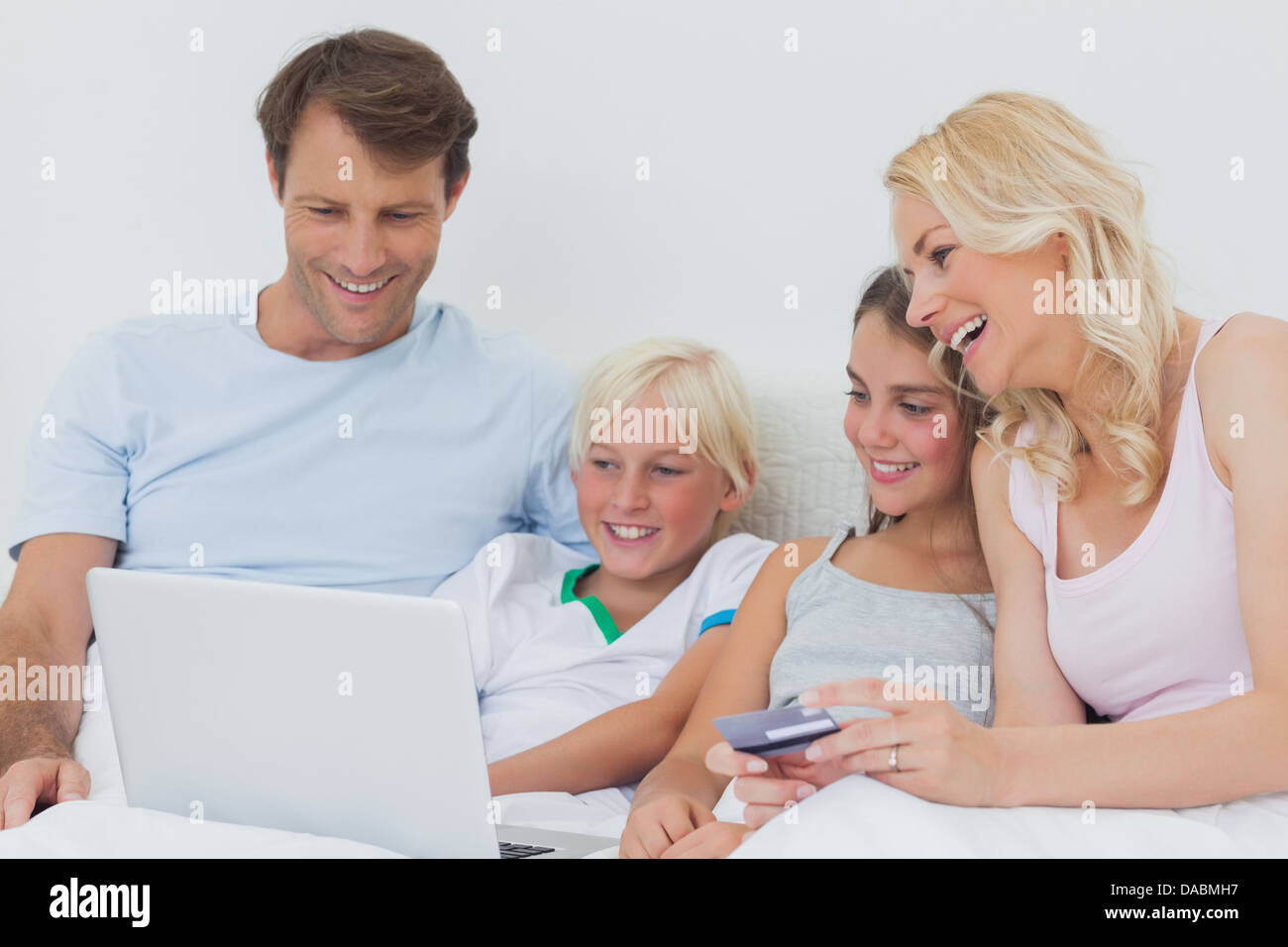 Family using computer and credit card in bed Stock Photo - Alamy