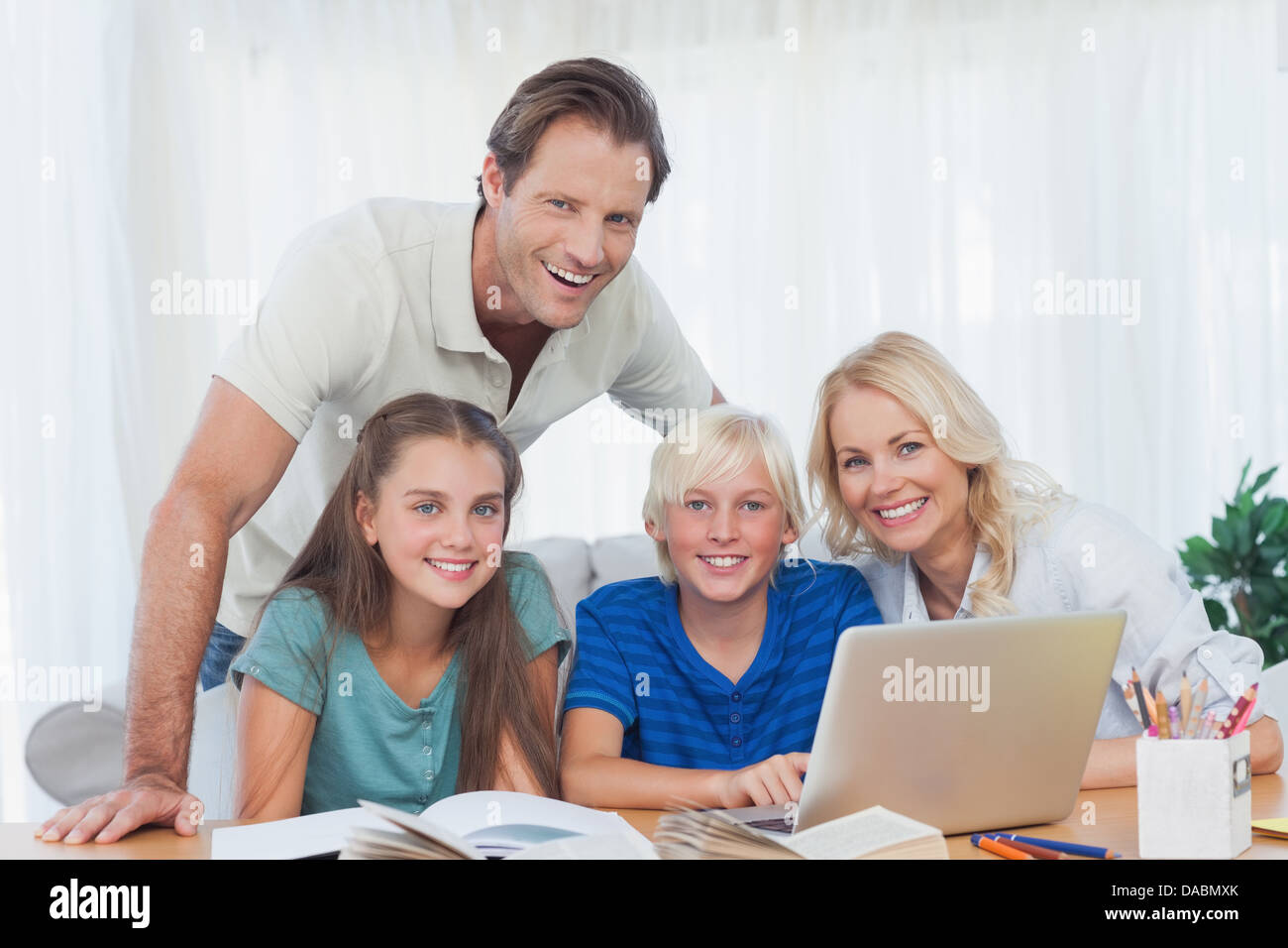Smiling family using the laptop together to do homework Stock Photo - Alamy