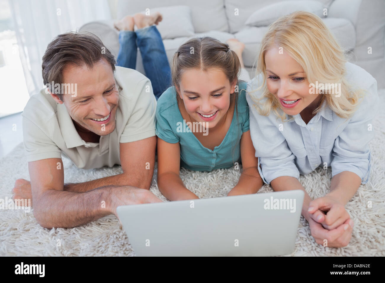Happy parents and daughter using a laptop Stock Photo - Alamy