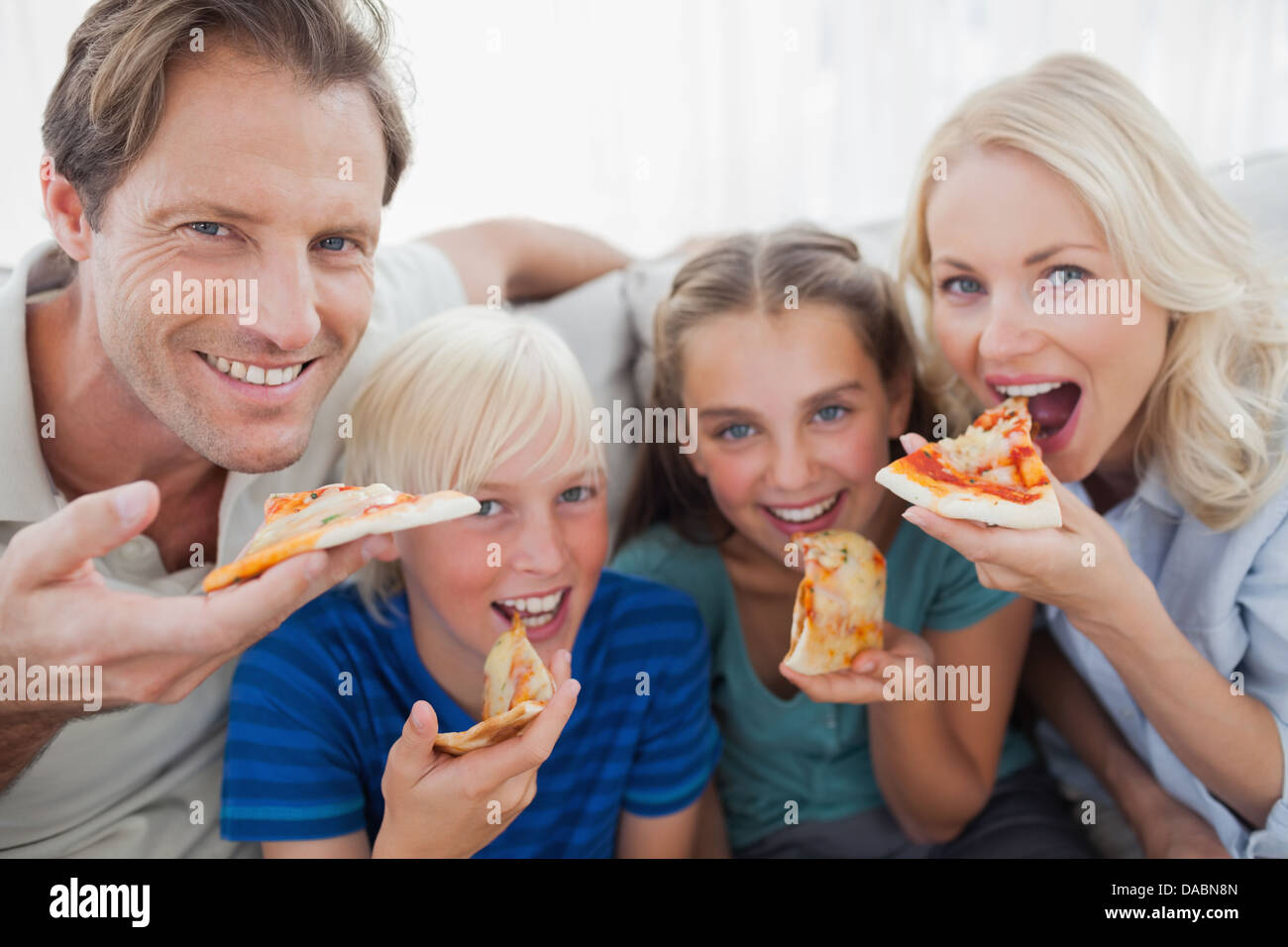Smiling family eating pizza Stock Photo - Alamy