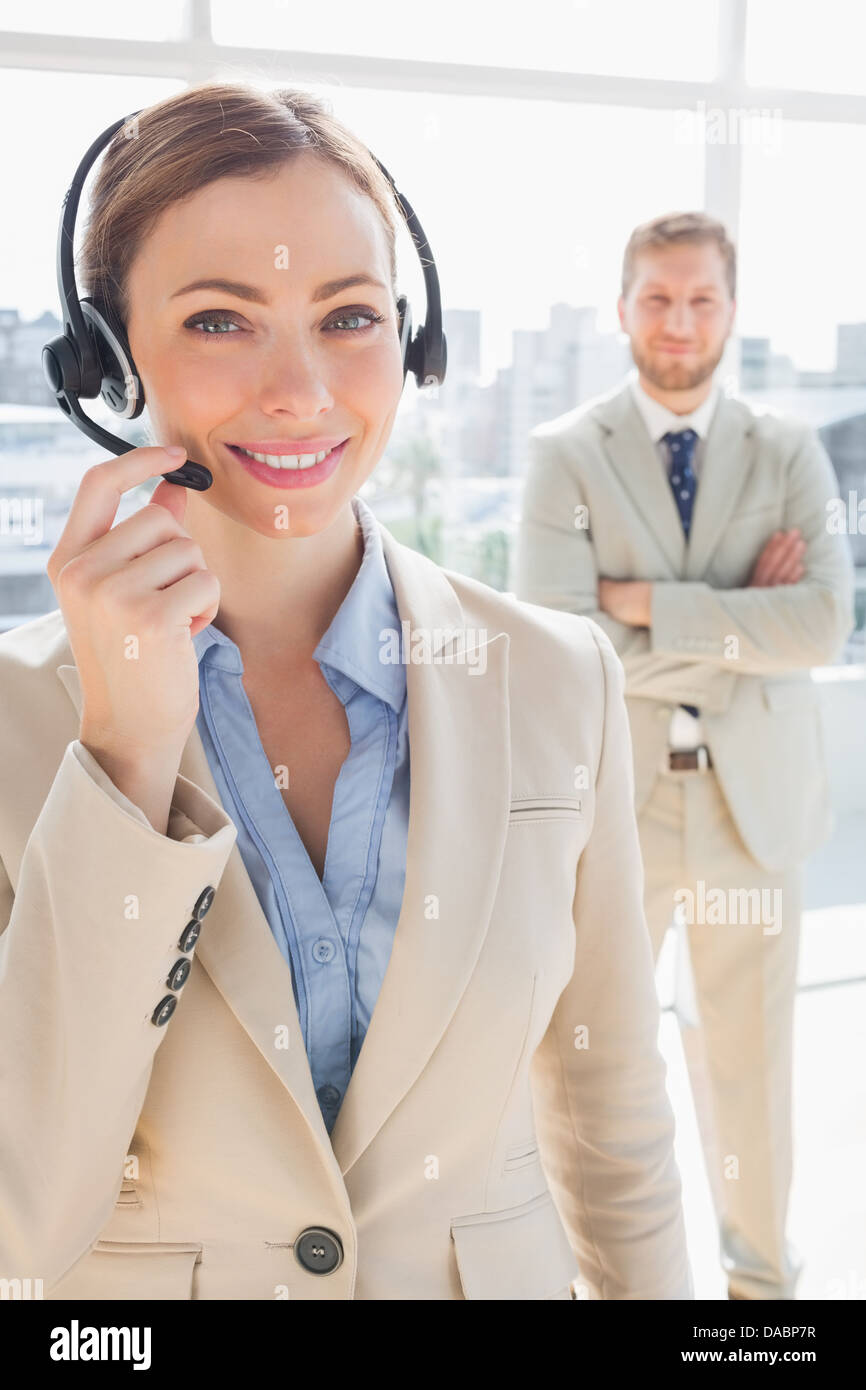 Smiling call centre agent with colleague behind her Stock Photo - Alamy