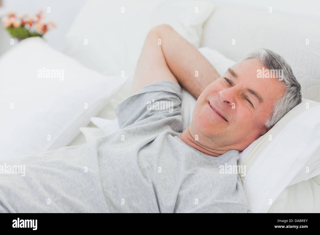 Smiling man relaxing in bed Stock Photo - Alamy