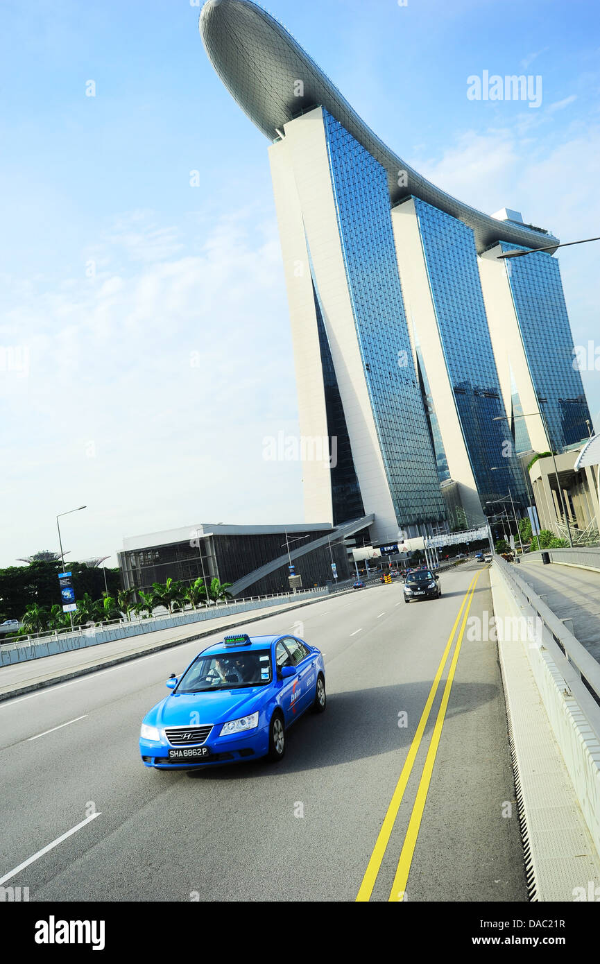 Taxi cab driving by the road in front of Marina Bay Sands hotel in ...