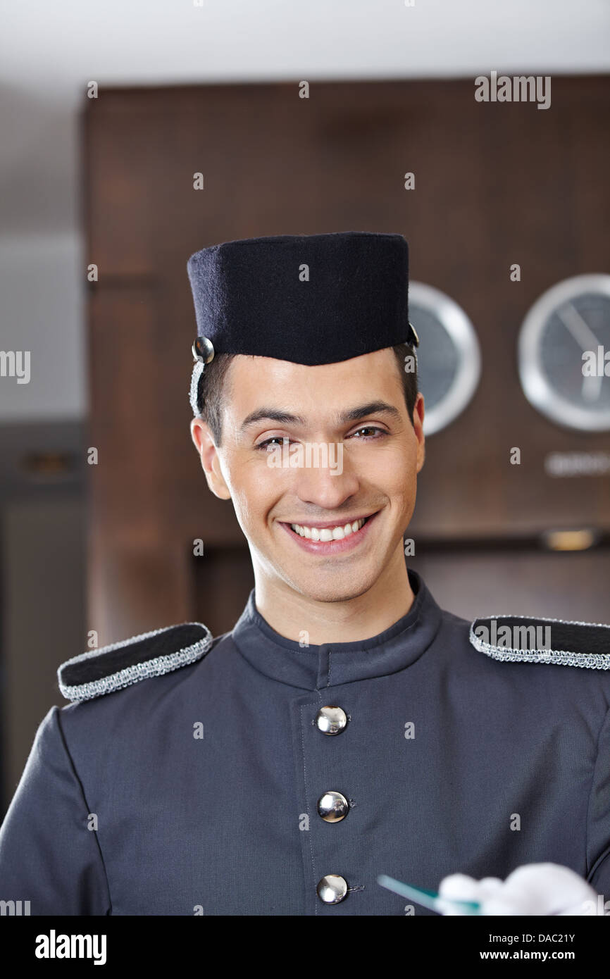 Happy hotel concierge smiling with key card in his hand Stock Photo - Alamy