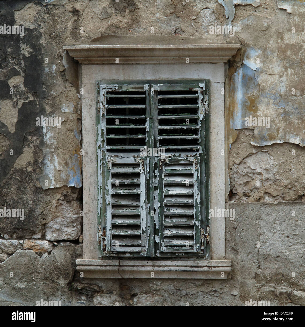 Shuttered window with weathered green shutters and peeling paint on a ...
