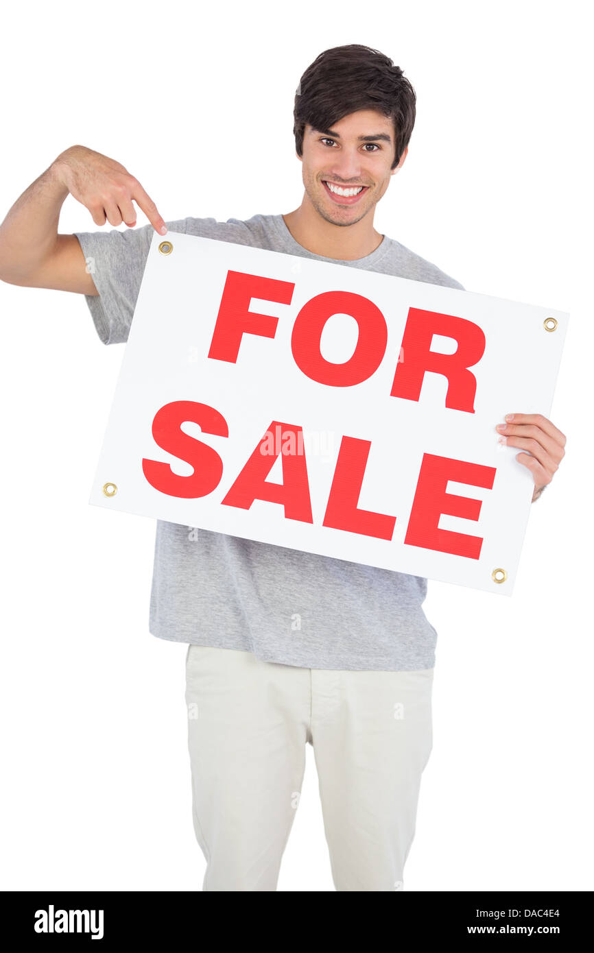 Smiling man pointing at for sale sign Stock Photo - Alamy