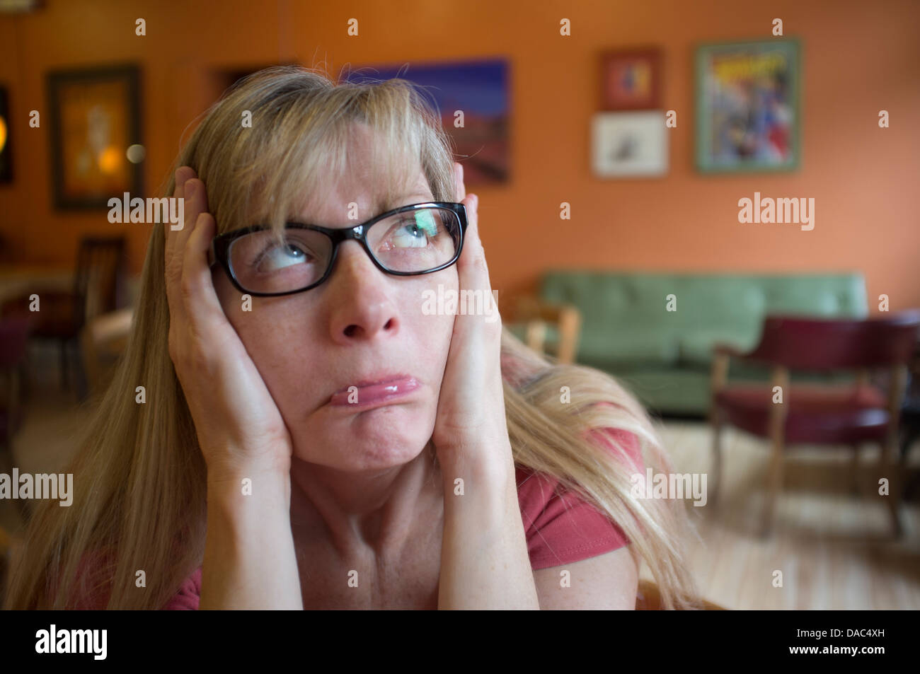 Female wearing glasses pulling cheeks back sticking bottom lip out and ...