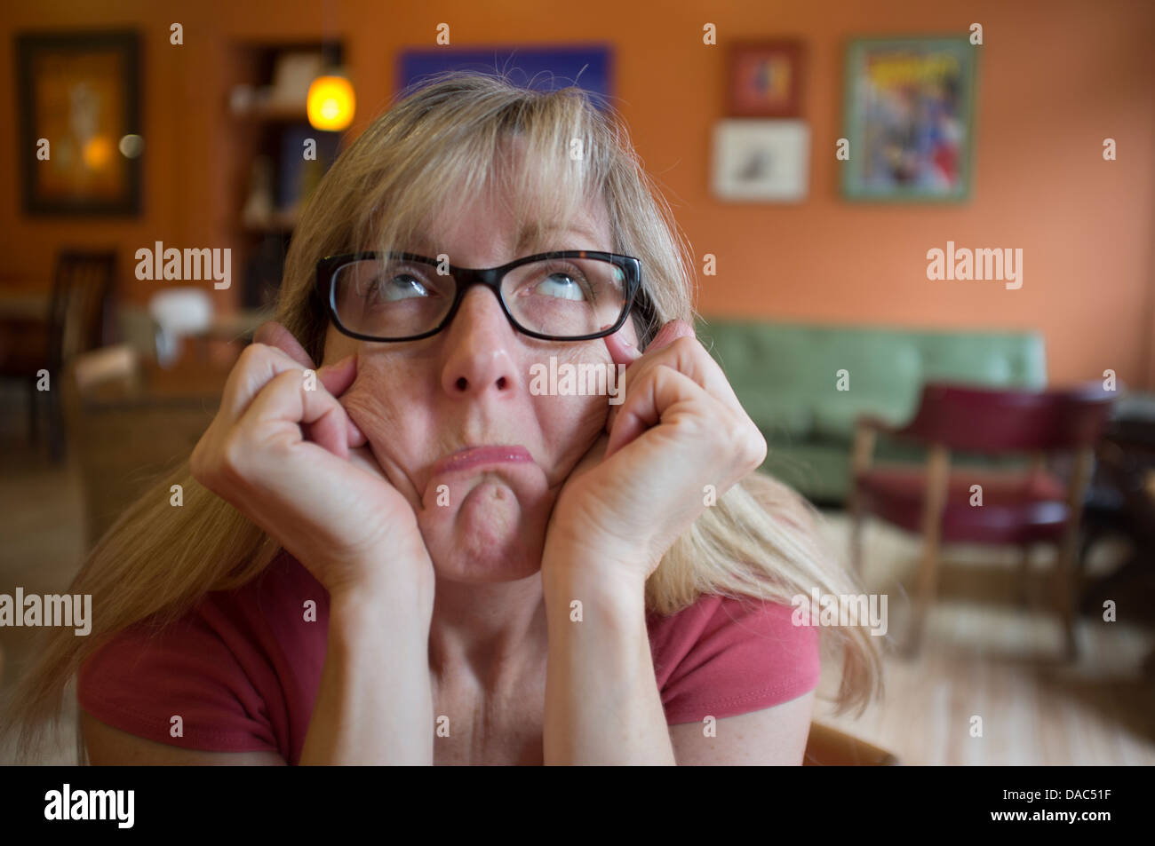 Closeup of woman with glasses making a silly expression looking upward ...
