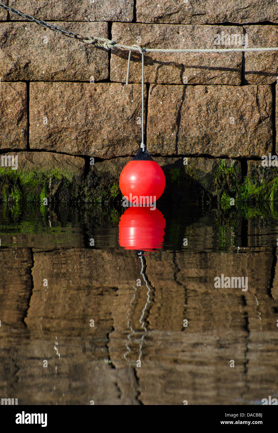 A red buoy reflects peacefully in the water in a harbor Stock Photo - Alamy