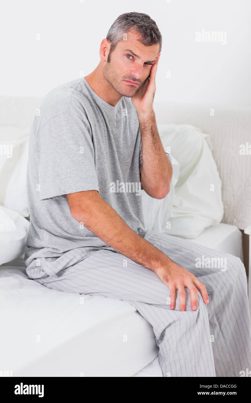 Worried man sitting in bed Stock Photo - Alamy
