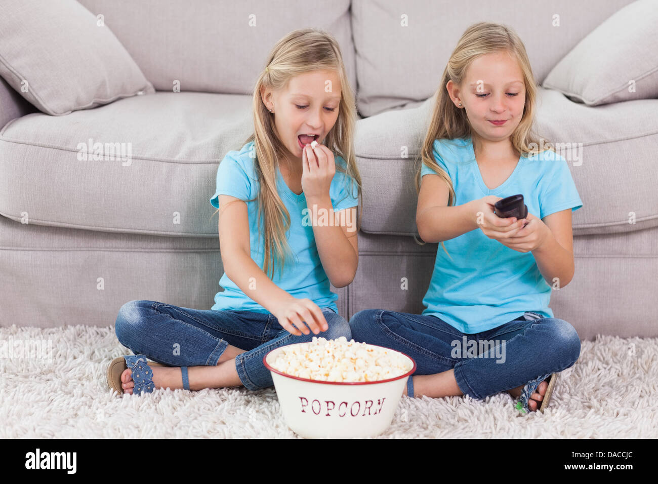 Twins eating popcorn and watching television Stock Photo - Alamy