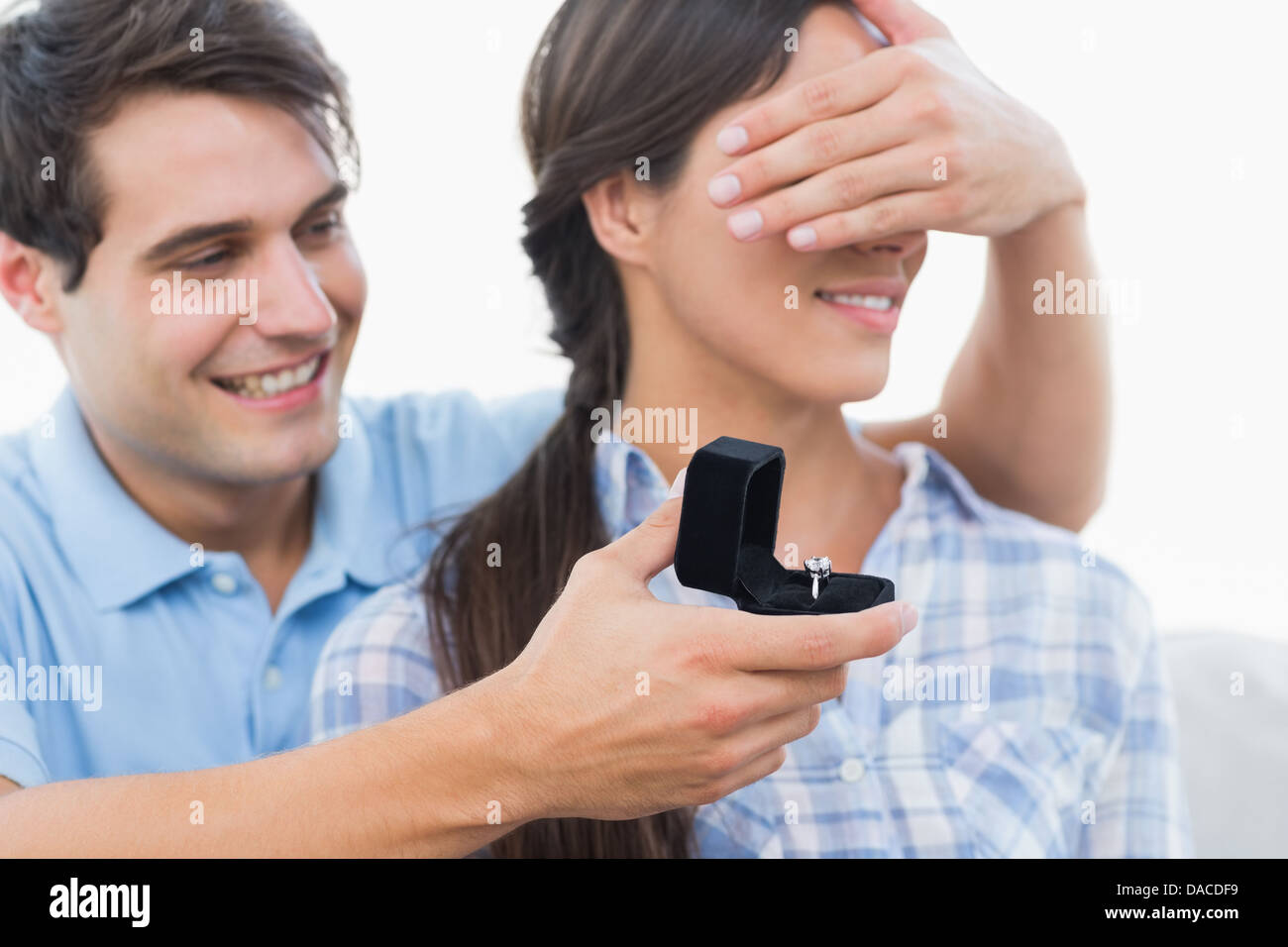 Man hiding his partners eyes and offering her an engagement ring Stock ...