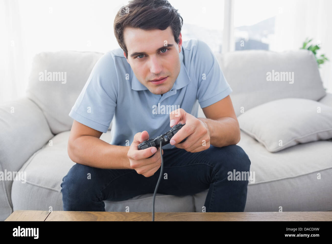 Man playing video games while he is sat on a sofa Stock Photo - Alamy