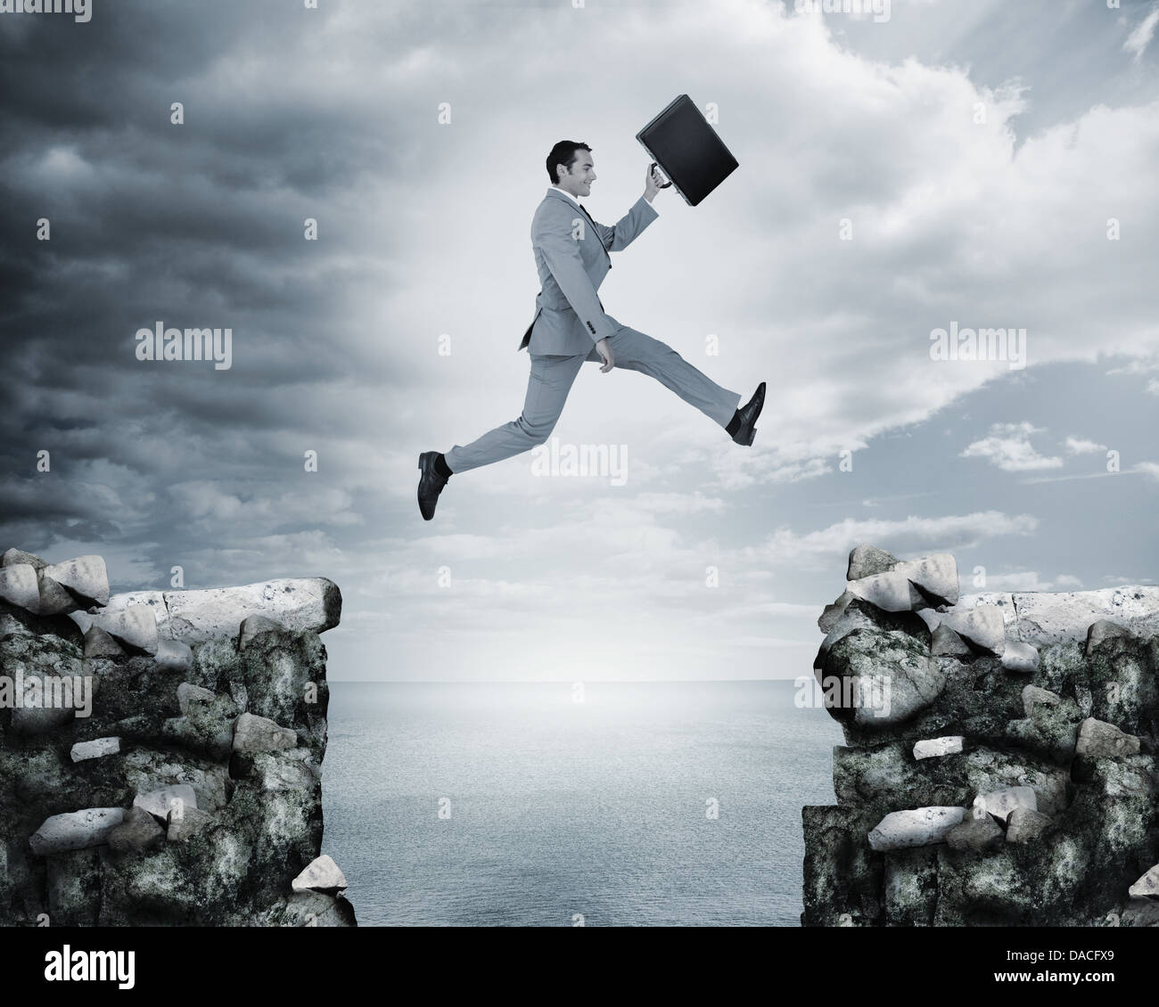 Businessman jumping a gap between cliffs Stock Photo - Alamy