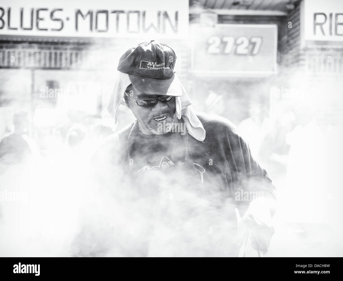African American man cooking ribs on an open grill with smoke from the ...